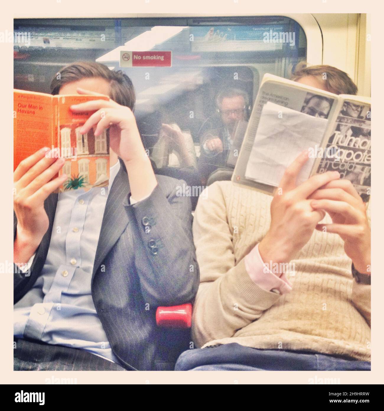 Commuters read a book while on the London Underground as part of their ...