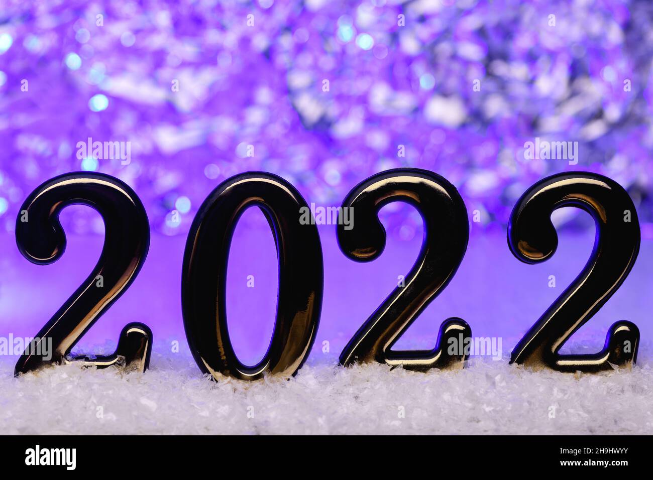 Black numbers 2022 on snow with purple backlight. New year backdrop ...