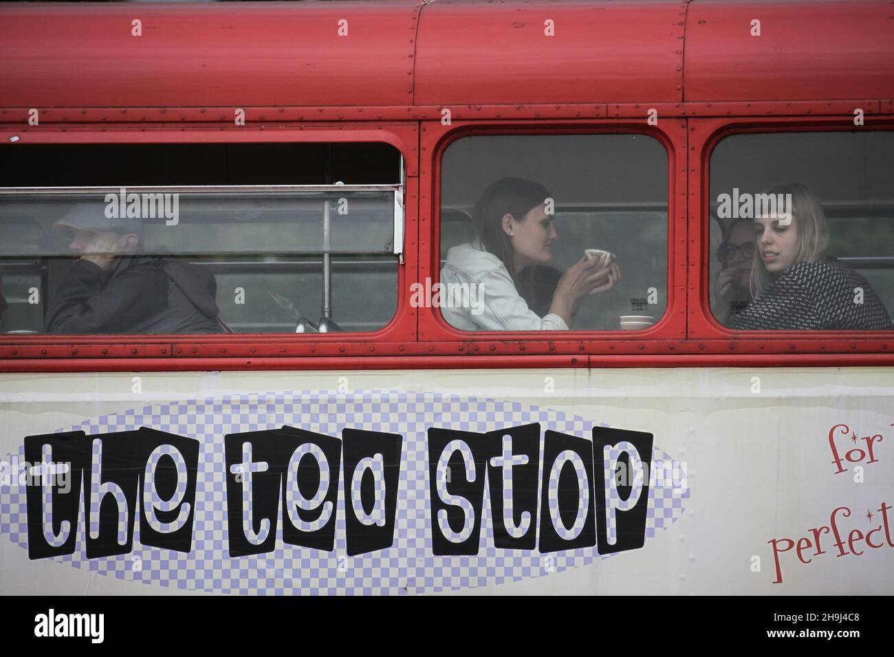 People eat and drink on a red bus at the 2014 End of the Road festival ...