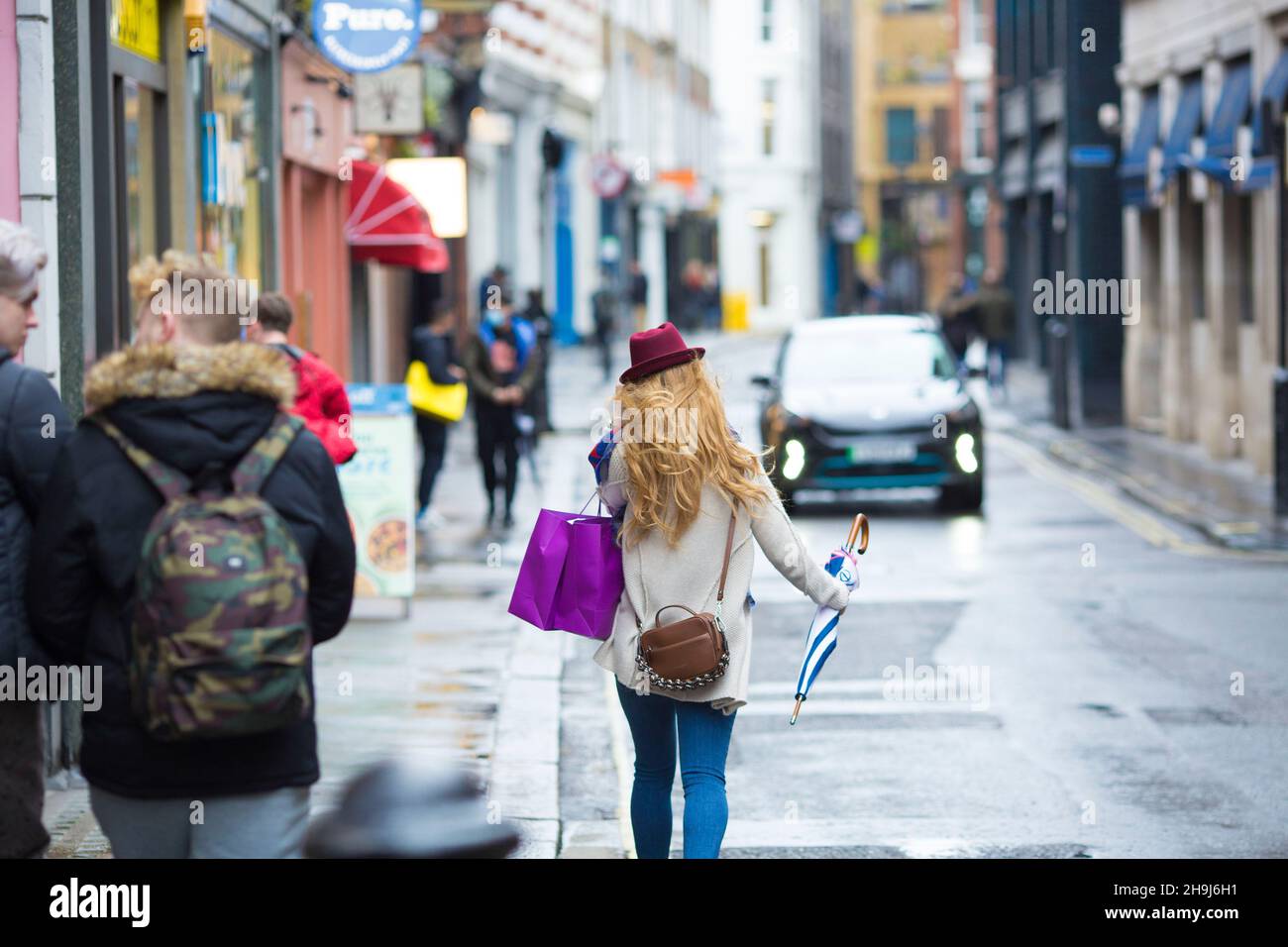 A wind blows a shopper’s hair as people go out in central London Stock ...