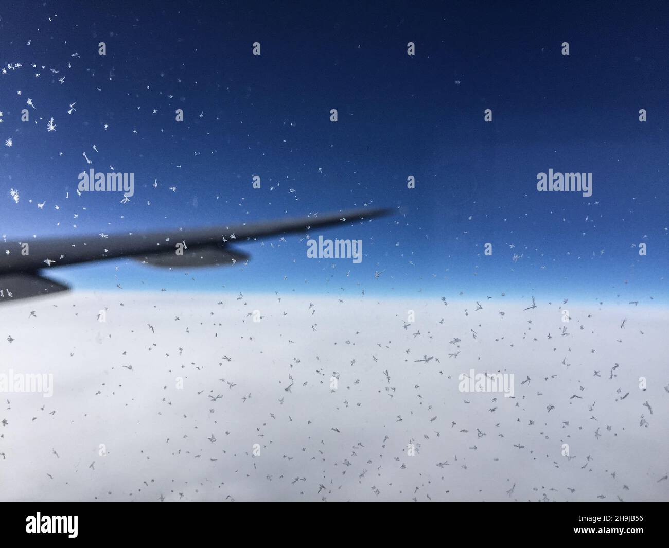 Photo taken from a plane showing a the plane's wing and snow flakes ...