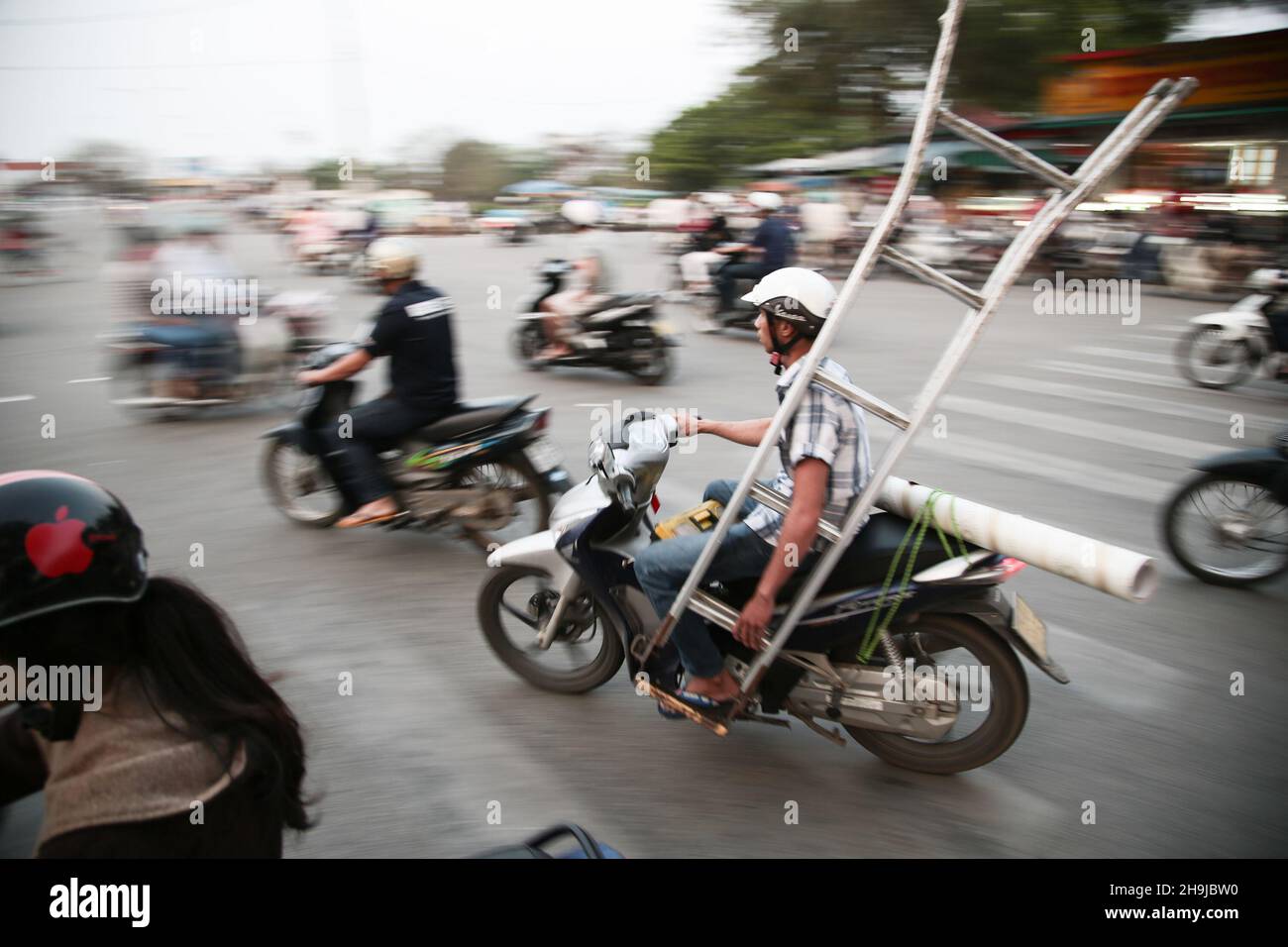A man carrying a ladder riding a motorbike on the streets of Hue in ...