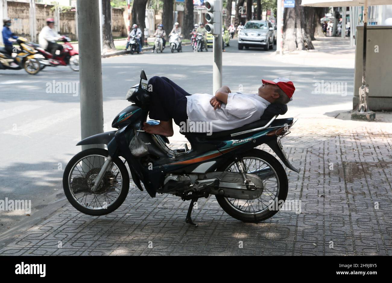 A man taking a nap on his motorbike in Ho Chi Min City in Vietnam. From ...