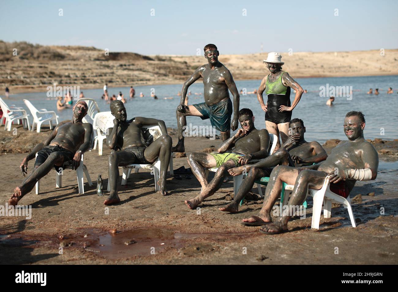 Bathers pose for photos next to the Dead Sea after covering themselves ...