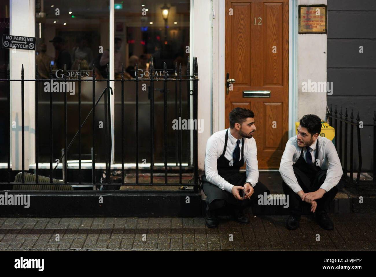 Two waiters taking a rest outside a restaurant on Bateman Street in ...
