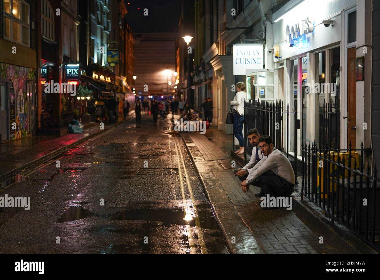 Two waiters taking a rest outside a restaurant on Bateman Street in ...