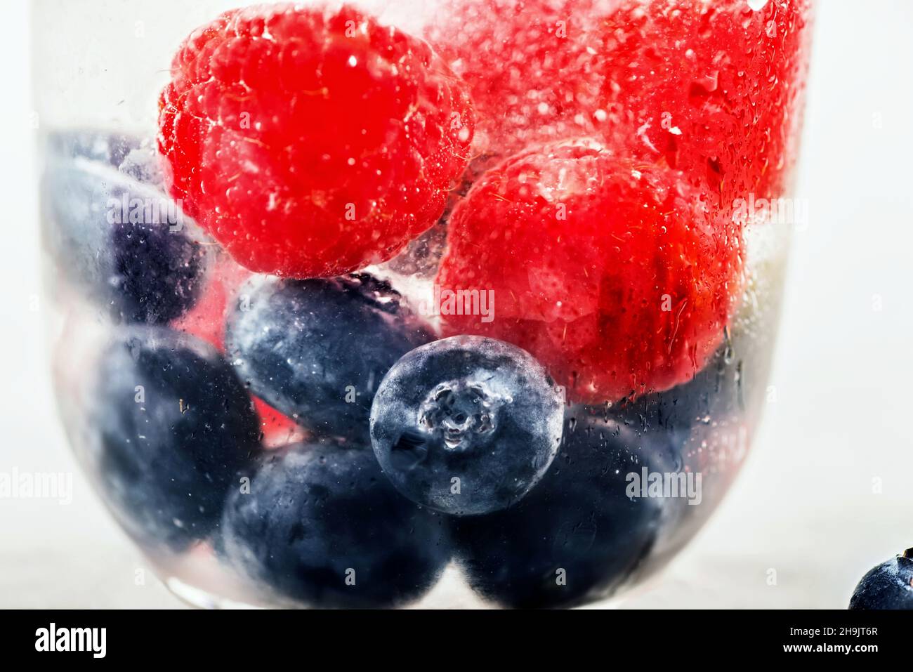 Blueberry and raspberry in glass with cold soda water drink ...