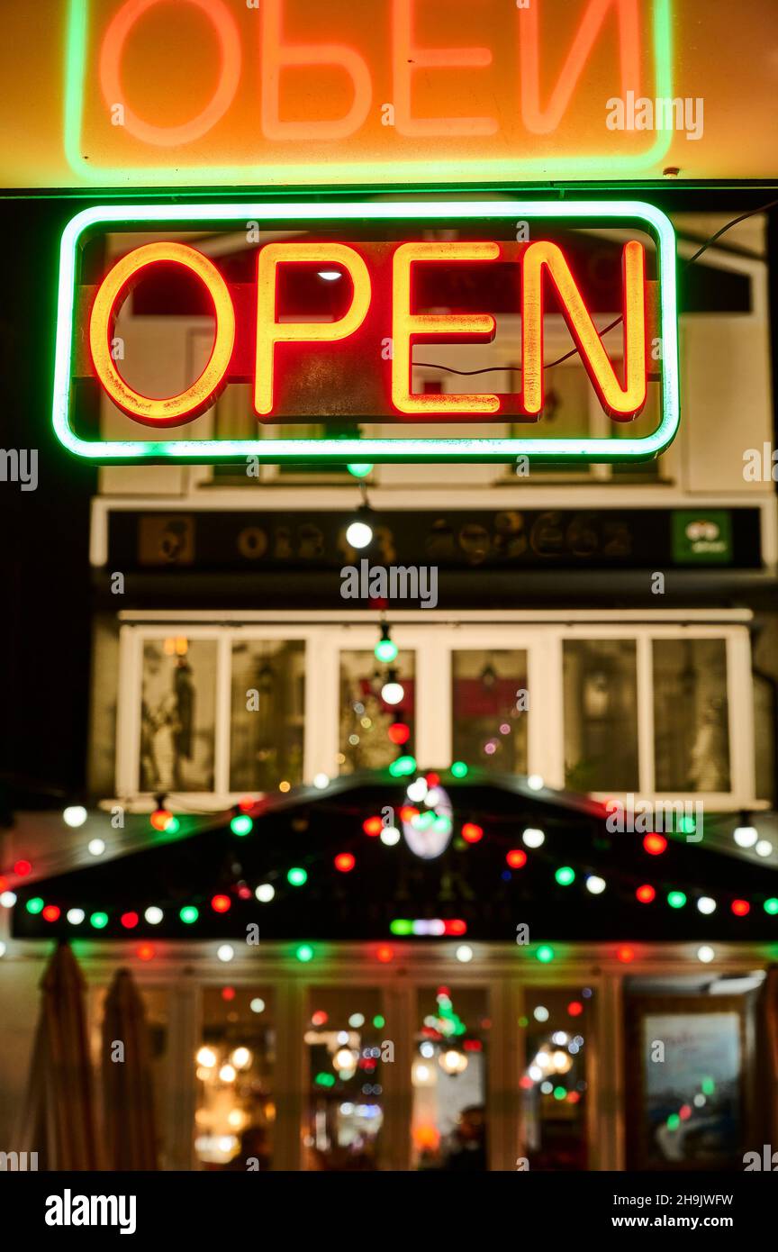 Neon open sign in front of restaurant at night reflected in ceiling ...