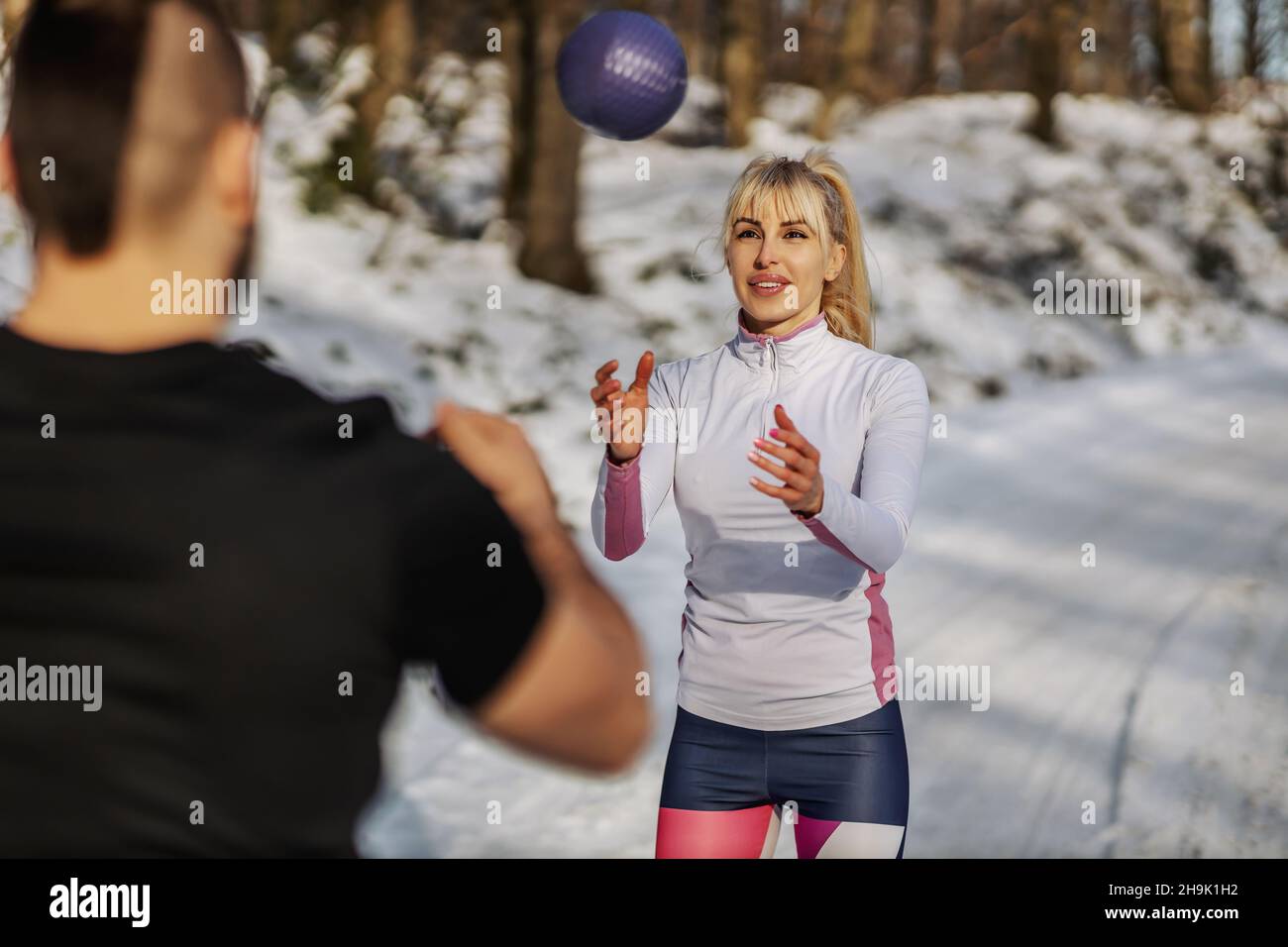 Sporty couple standing in snow in nature and doing warm up exercises ...