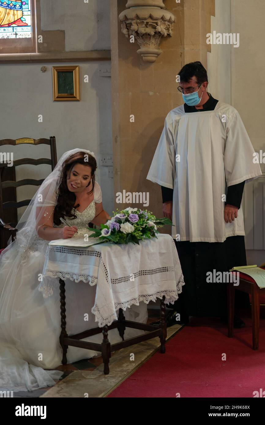 Samantha Fuller signs the wedding register, watched by a clergyman in a ...