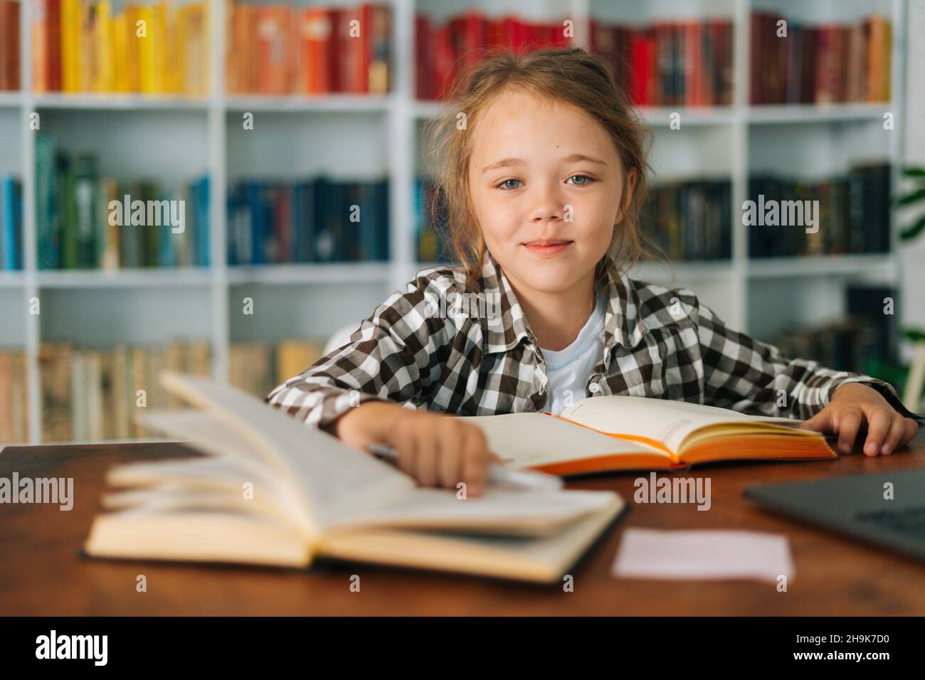 Close-up front view of pretty pupil child school girl doing homework ...