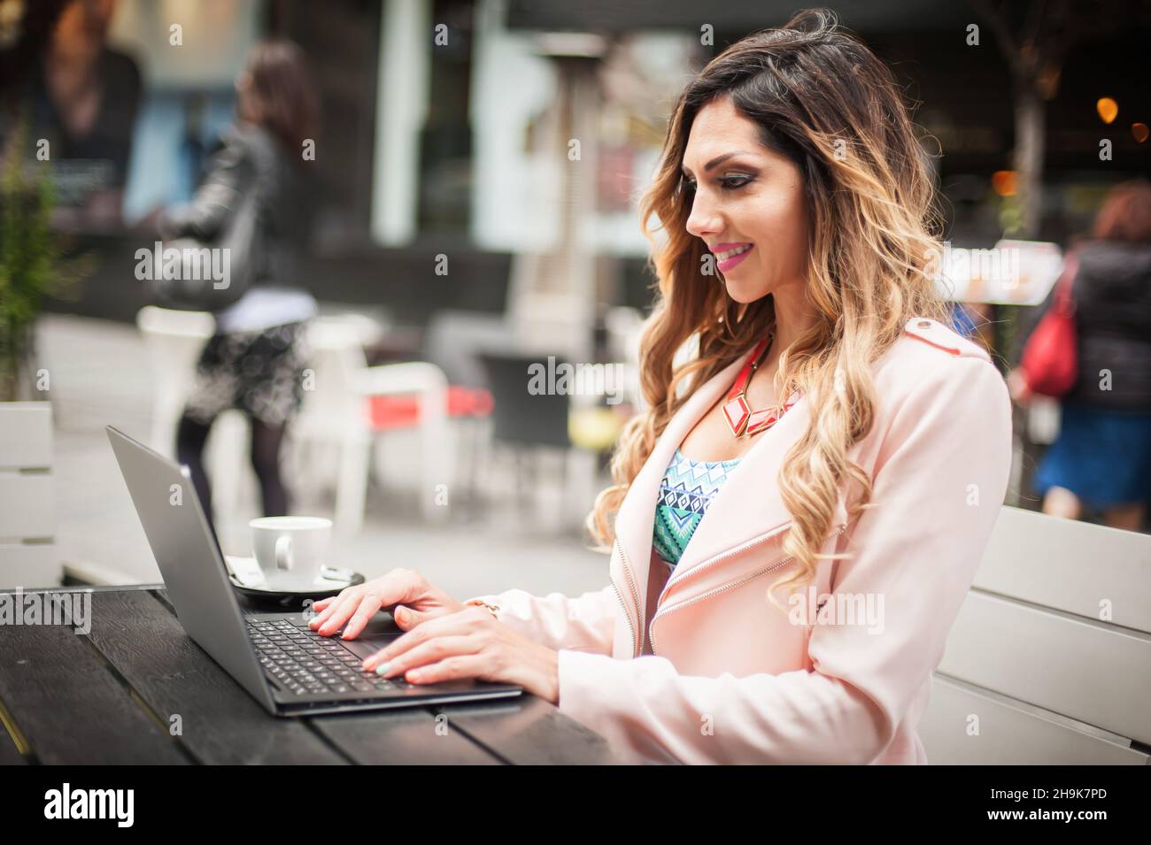 Young woman blogger freelancer influencer in outdoor cafe works on ...