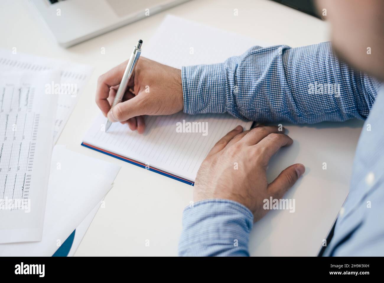 Man holding pen pencil in hand filling writing taking notes into notes ...