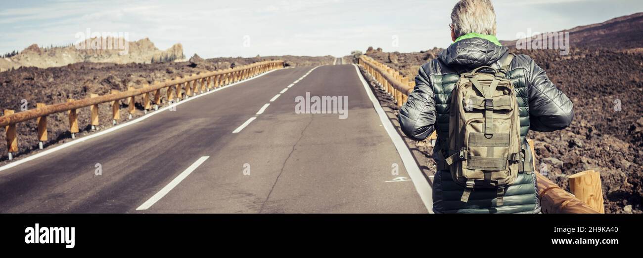 Old man travel lifestyle walking on a long straight road with backpack ...
