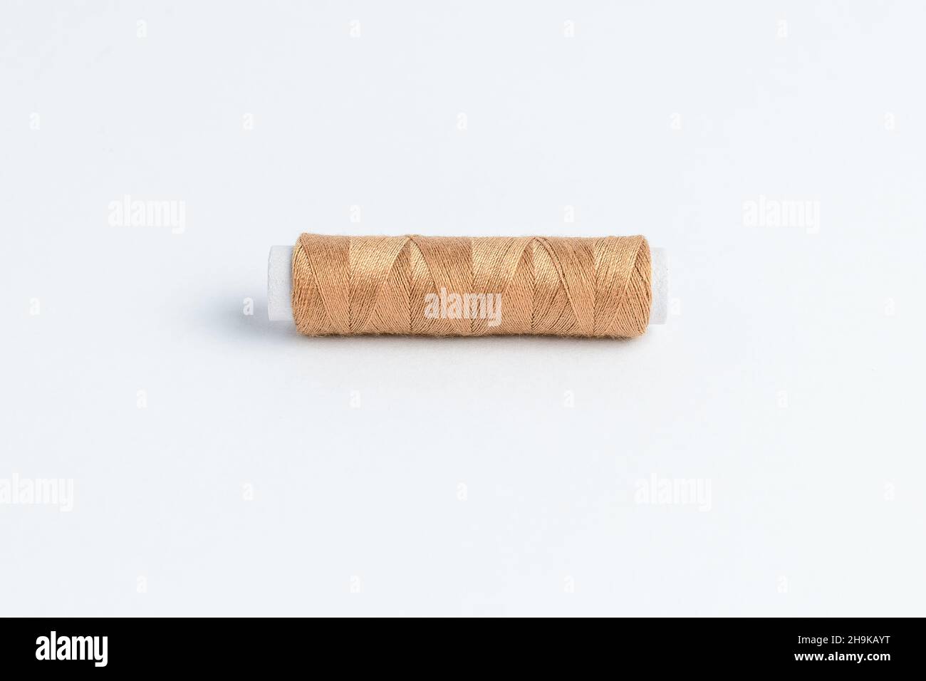 One vivid brown cotton spool of thread isolated on a white table Stock ...
