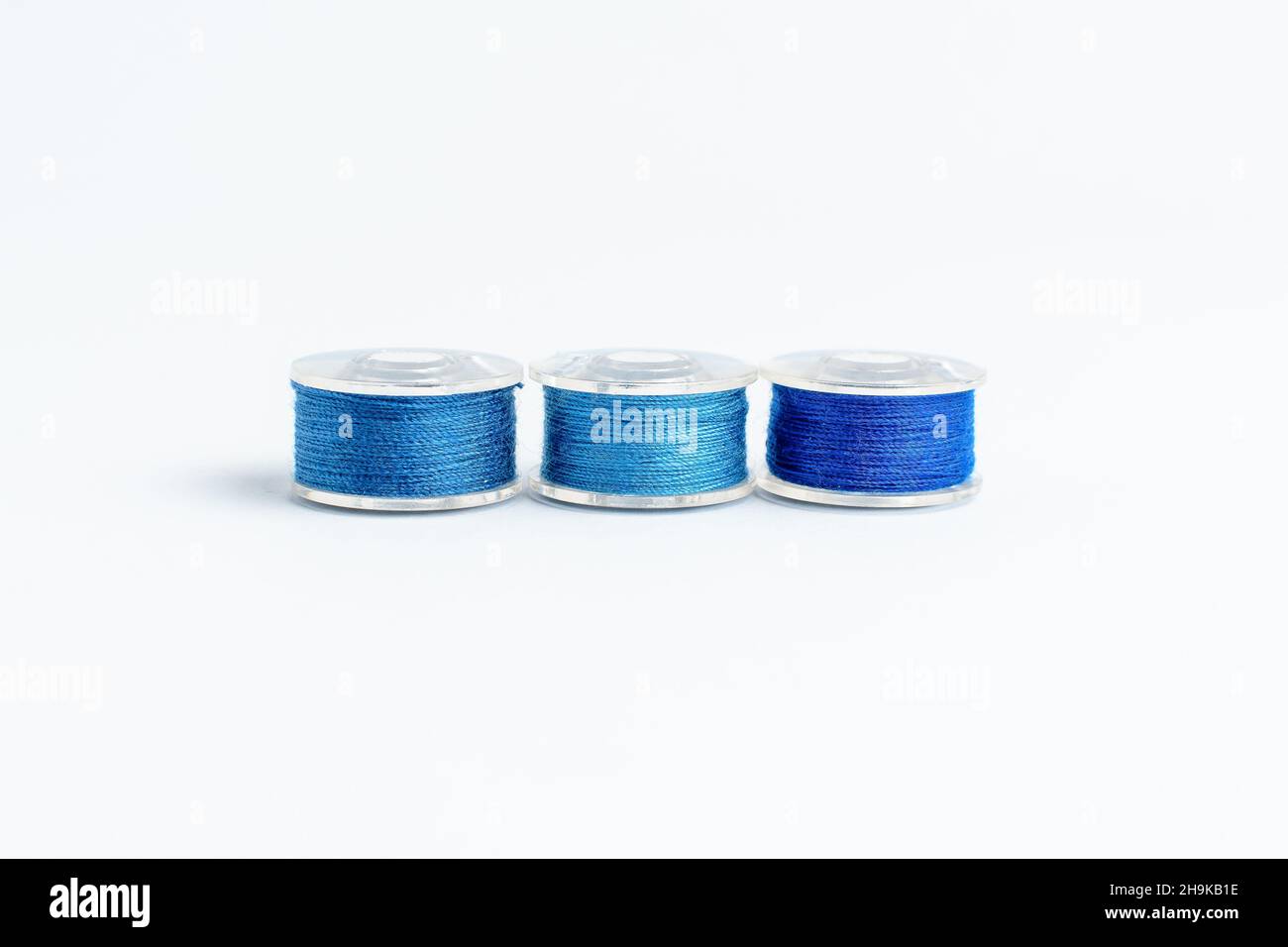 One line of mixed colourful blue spools of cotton thread displayed ...