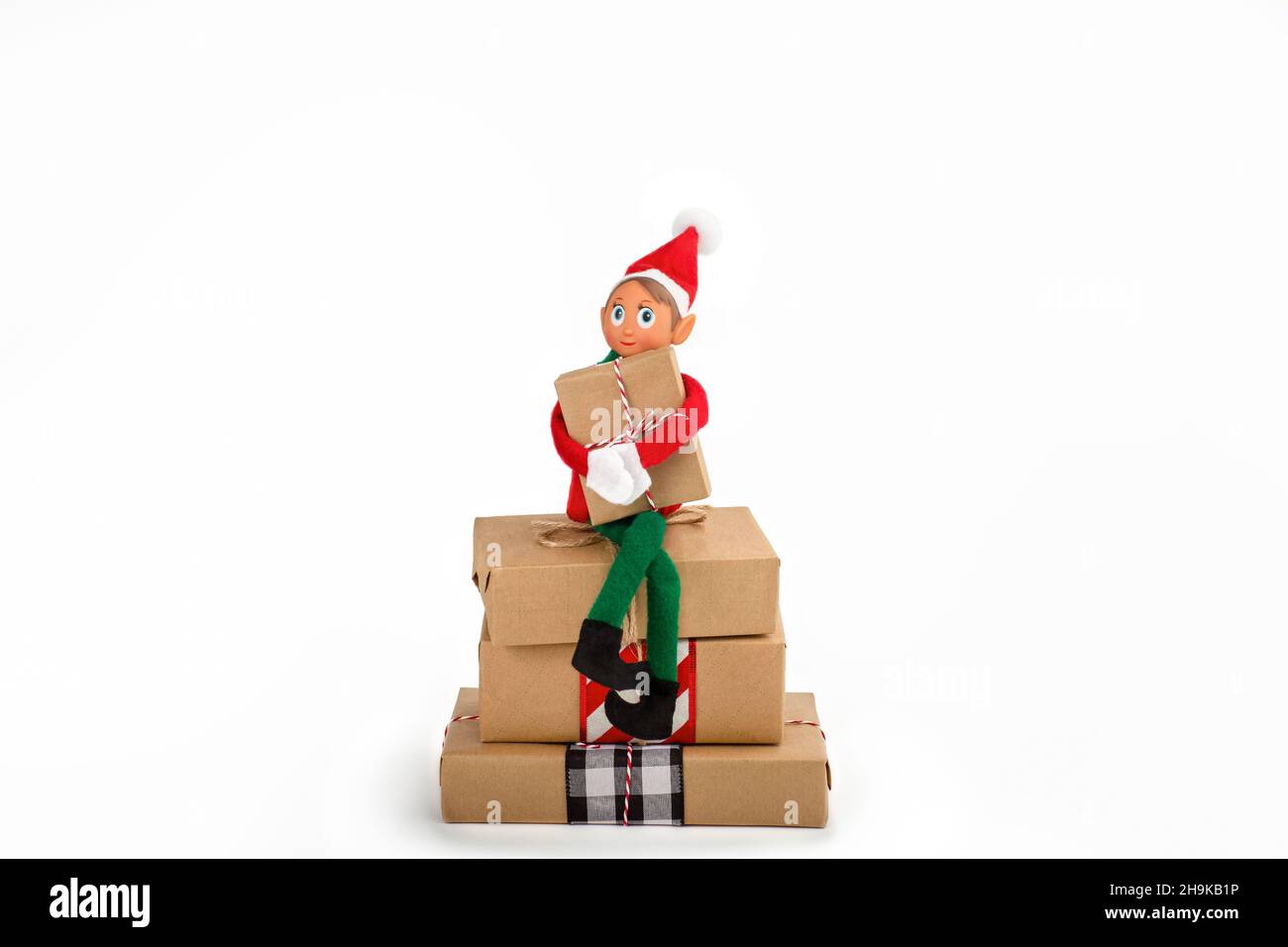 Christmas Elf sitting on a stack of gift boxes on an isolated white ...