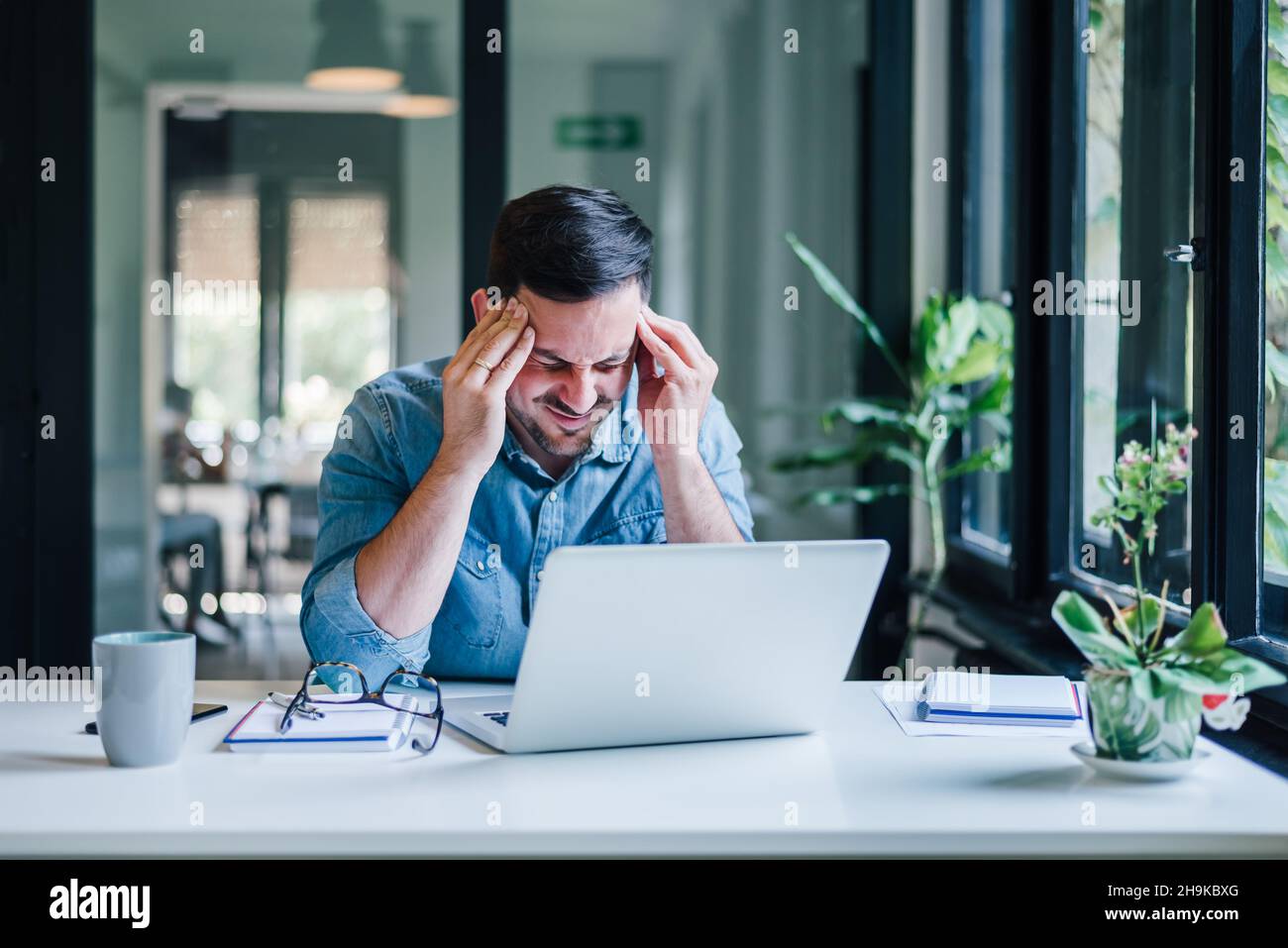 Businessman office working holding sore head pain from desk working and ...