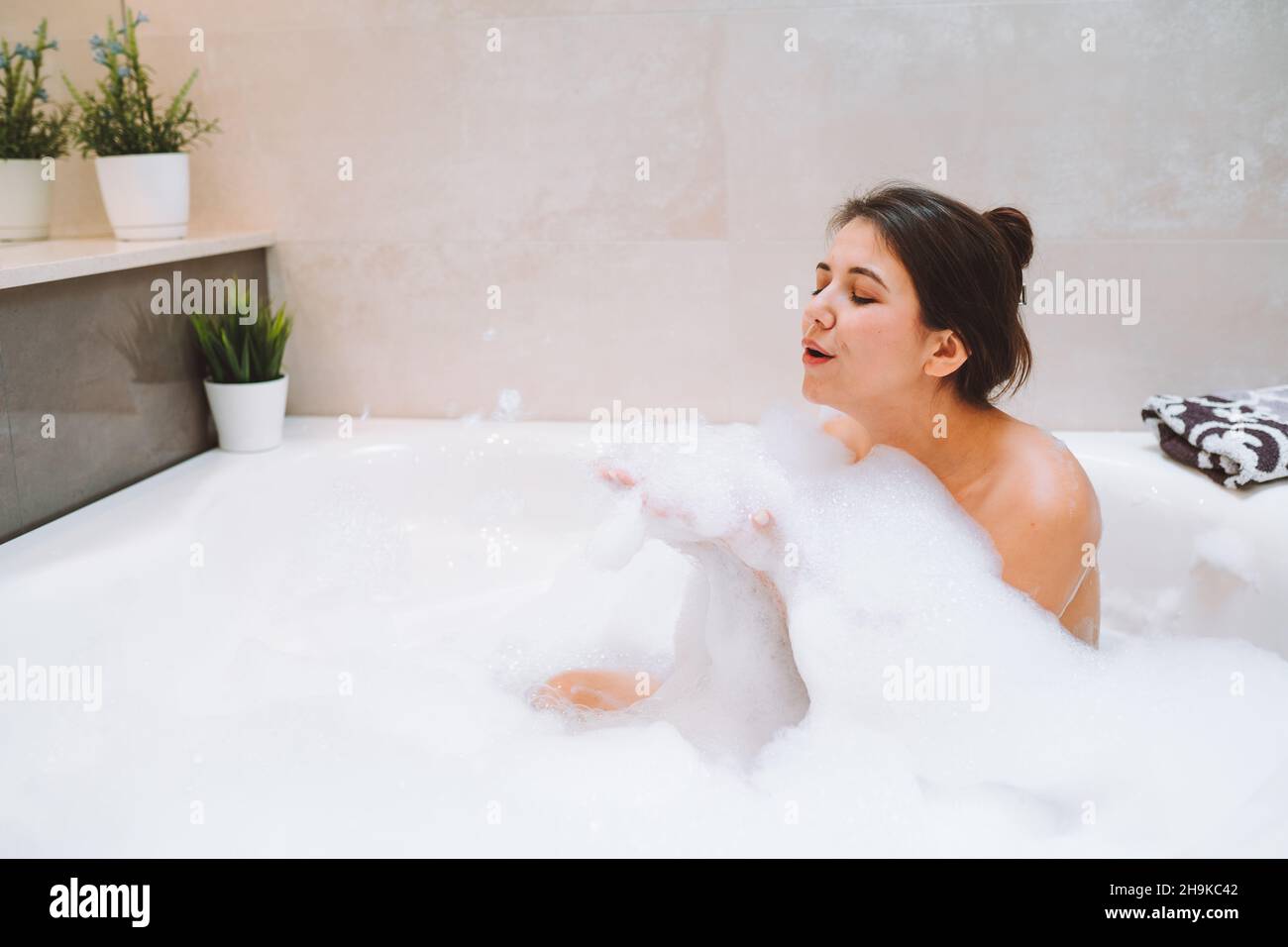 Portrait Of Young Woman Lying In Bath With Foam Spa Cleansing