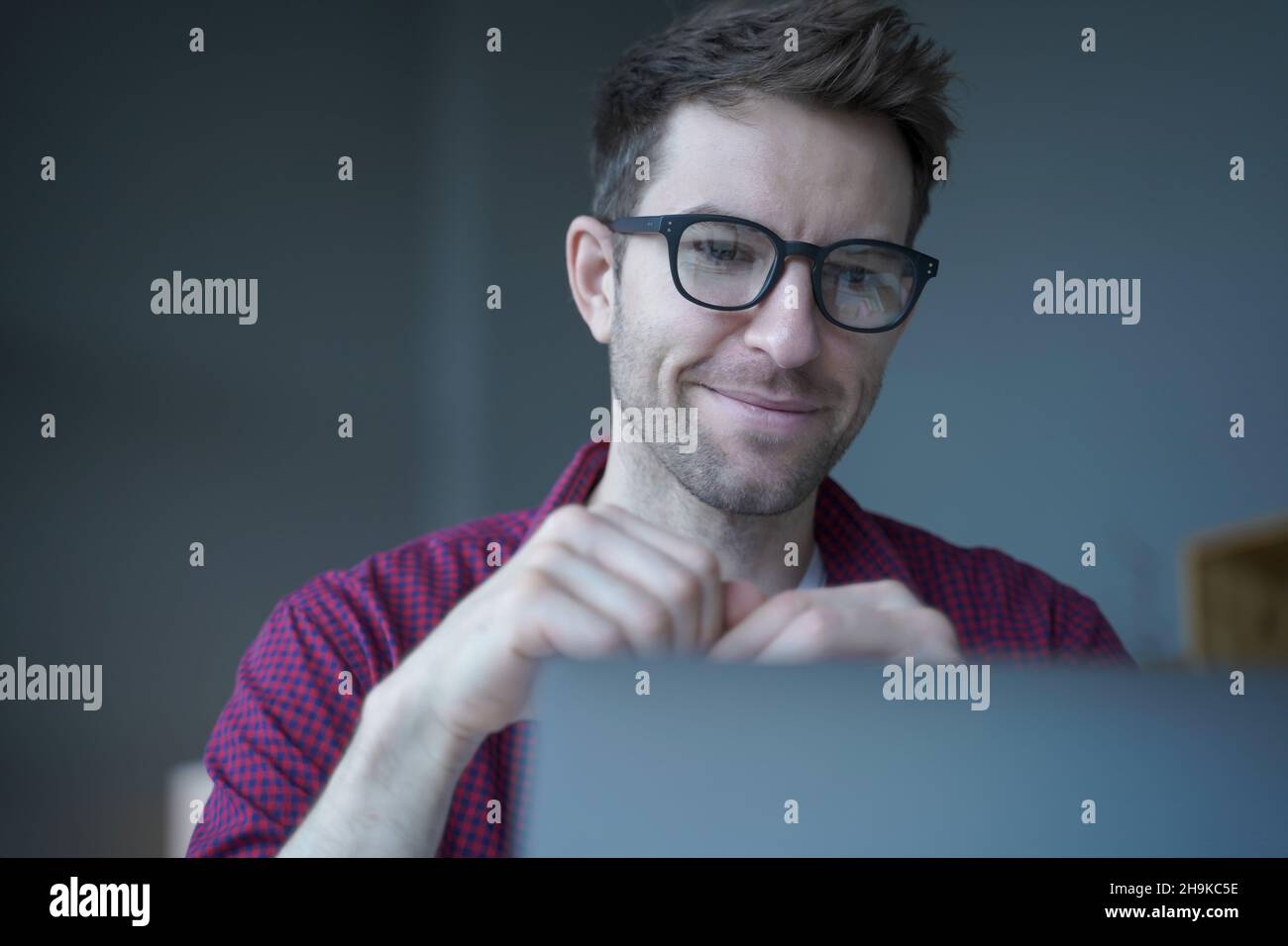 Smiling young German man freelancer in eyewear working remotely online ...