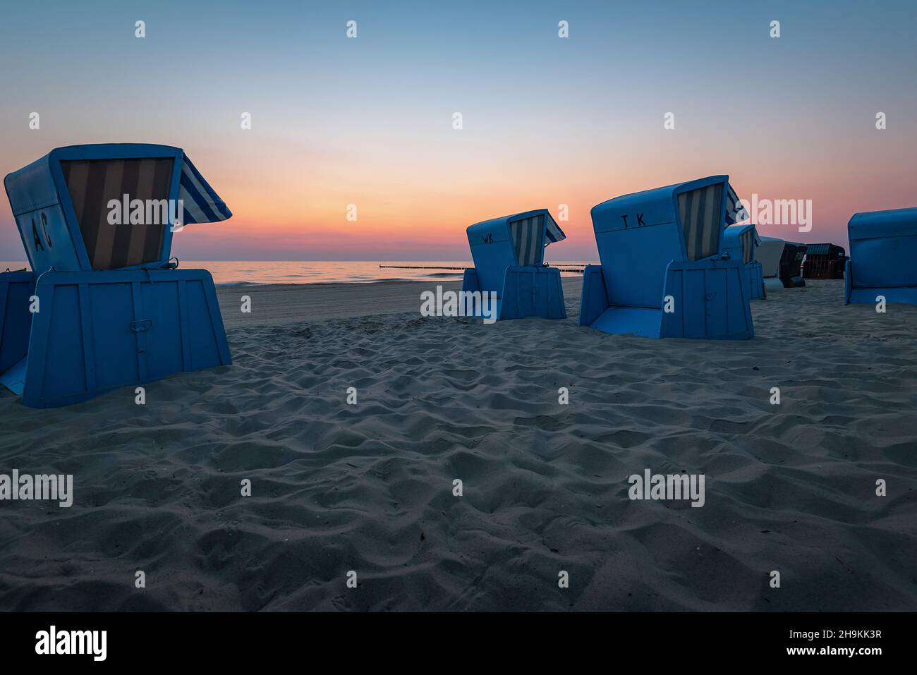 Hooded beach chairs on the sand gleaming under the sunrise Stock Photo ...