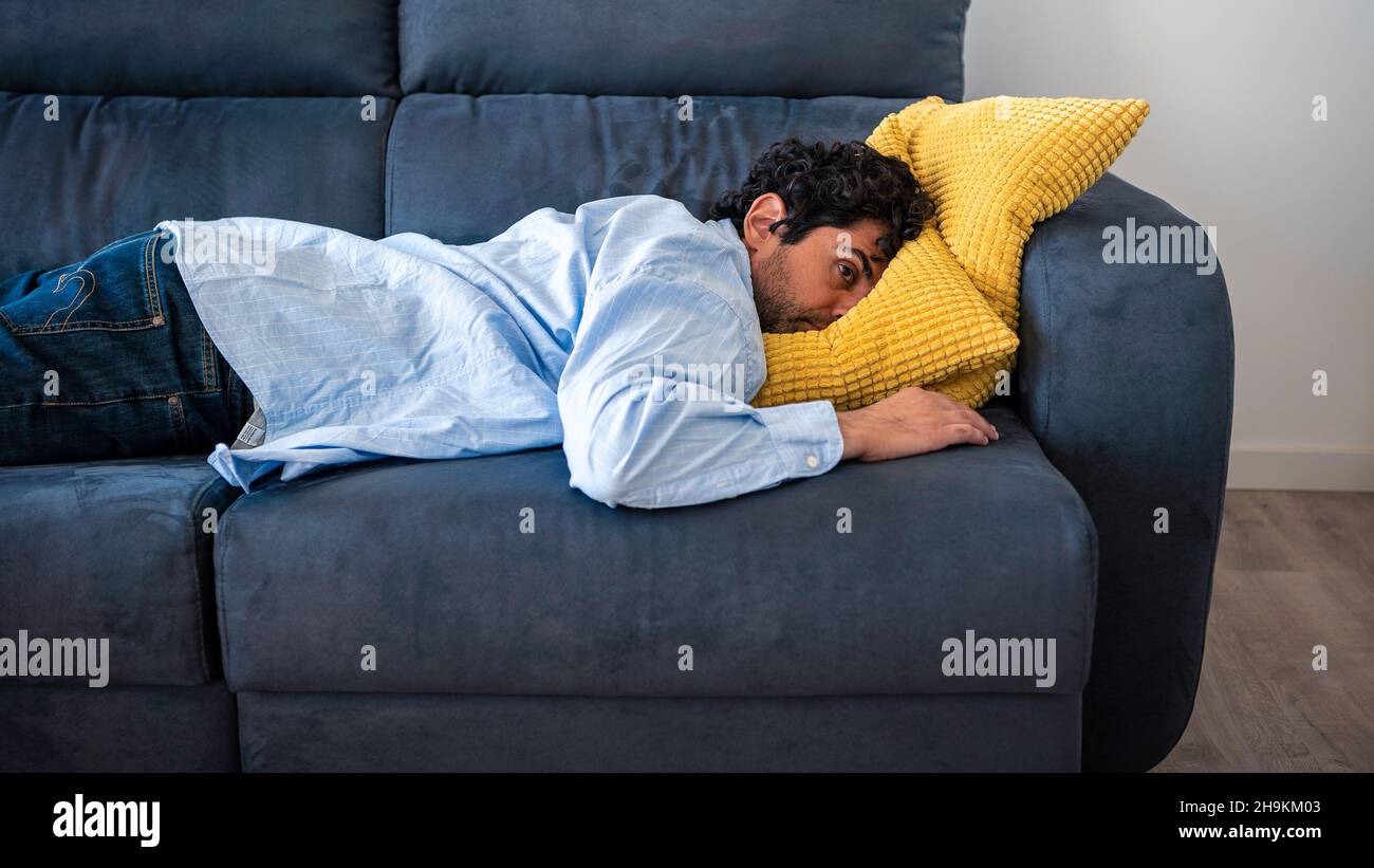 Tired frustrated millennial man at home, thinking over problems ...