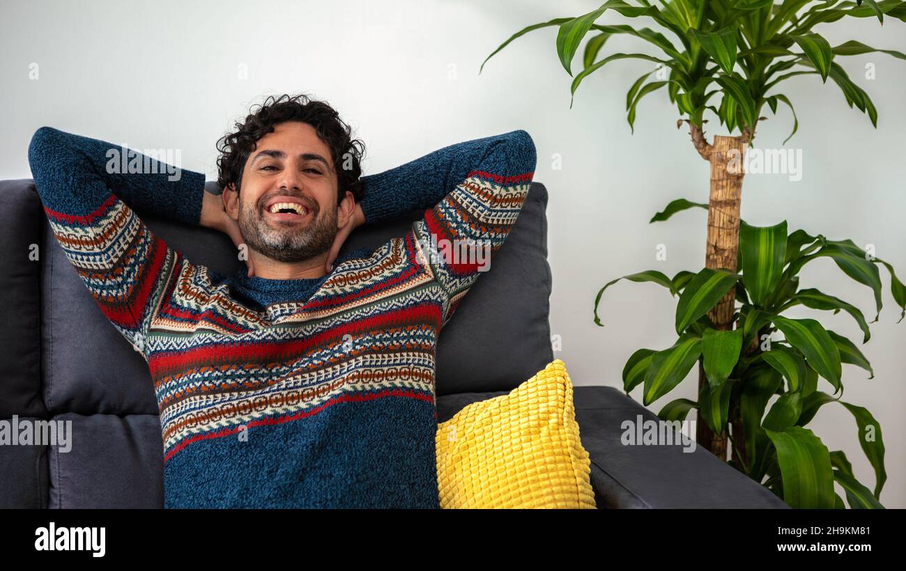 Portrait of happy latin man in casual relaxing on couch and smiling ...