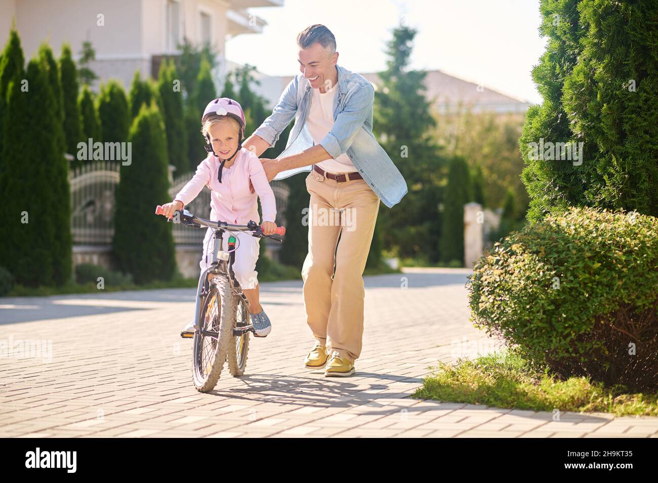 Dad helping his daughter learn riding a bike Stock Photo - Alamy