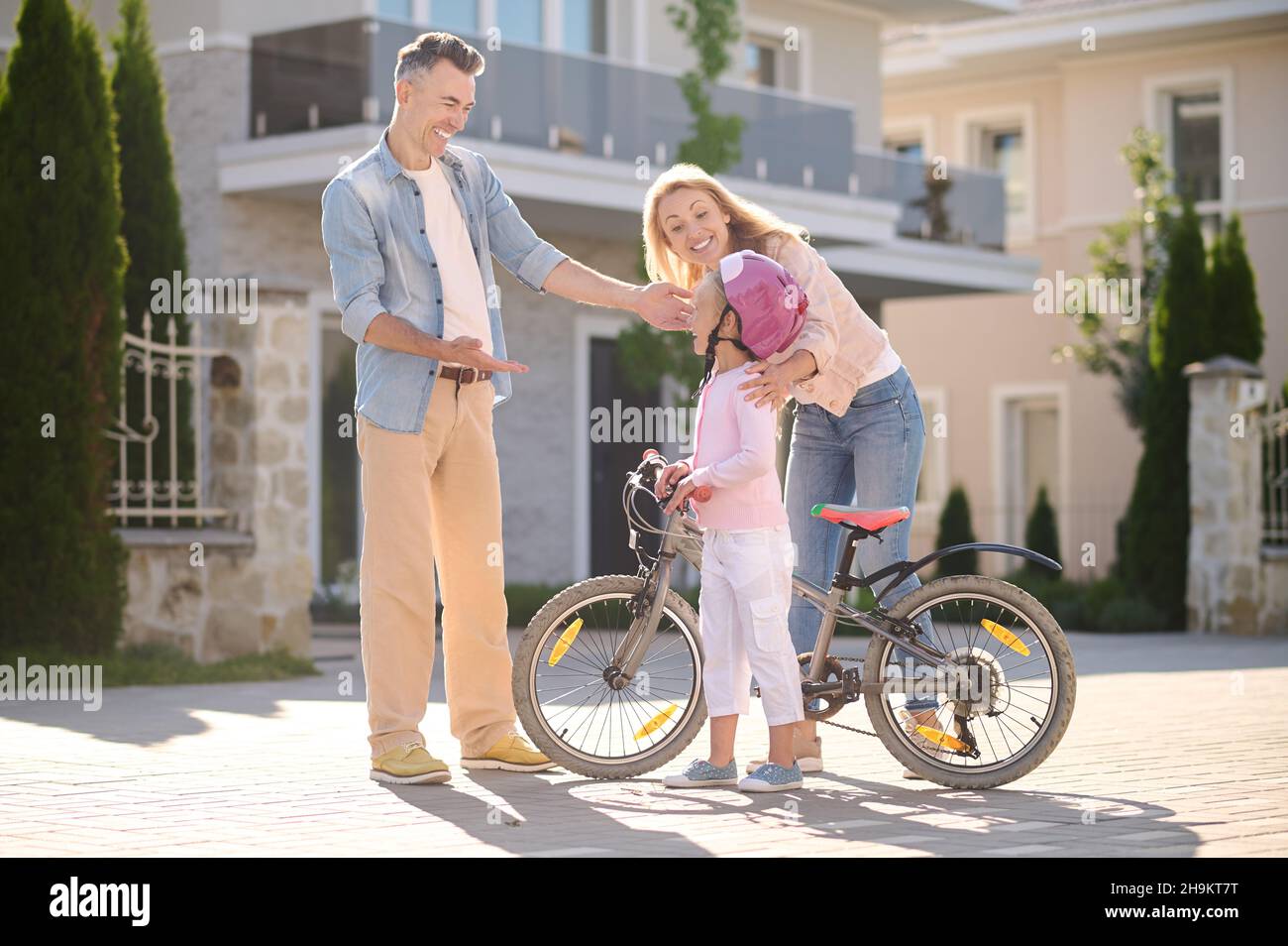 A girl riding a bike while her parents watching her Stock Photo - Alamy
