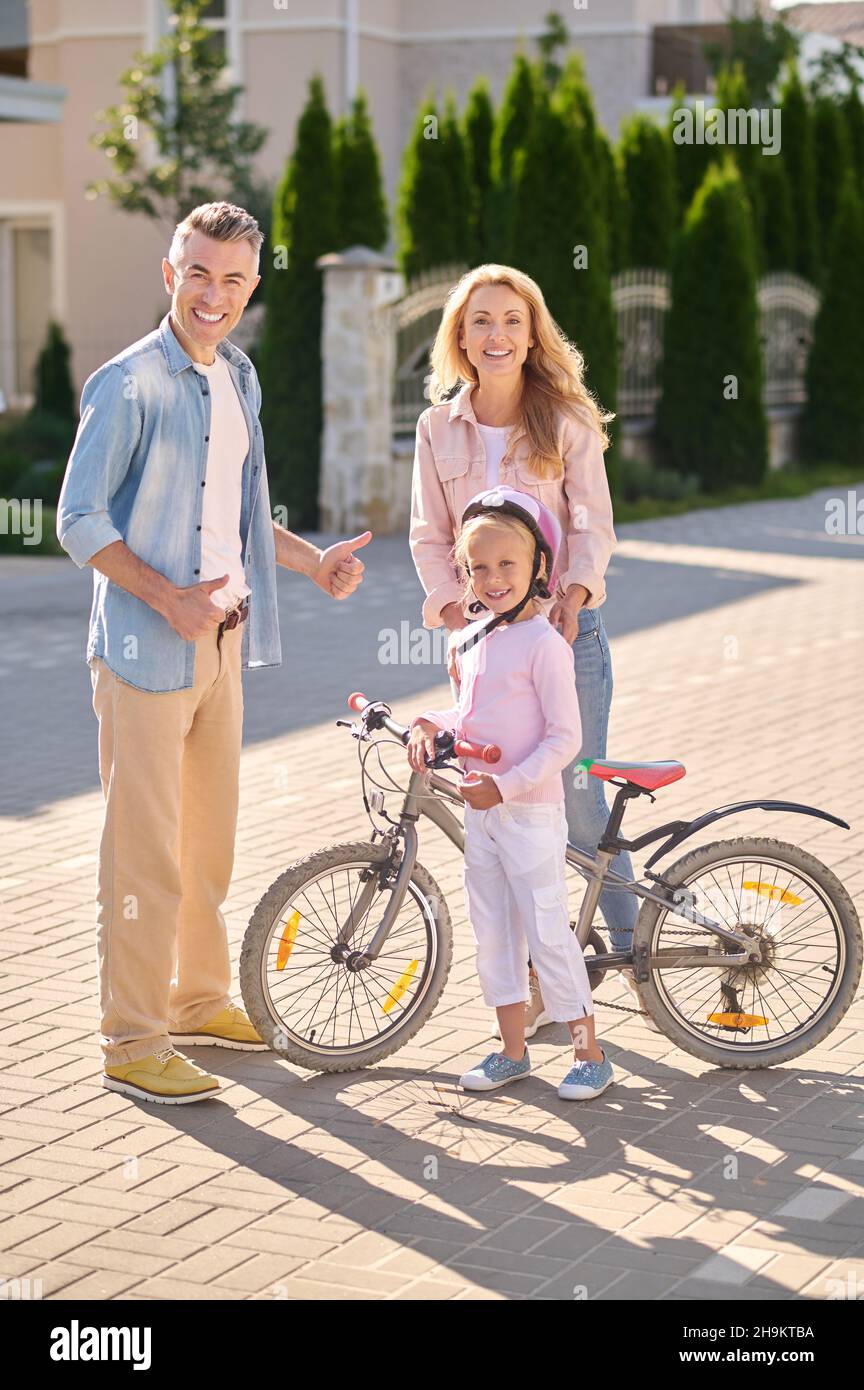A girl riding a bike while her parents watching her Stock Photo - Alamy