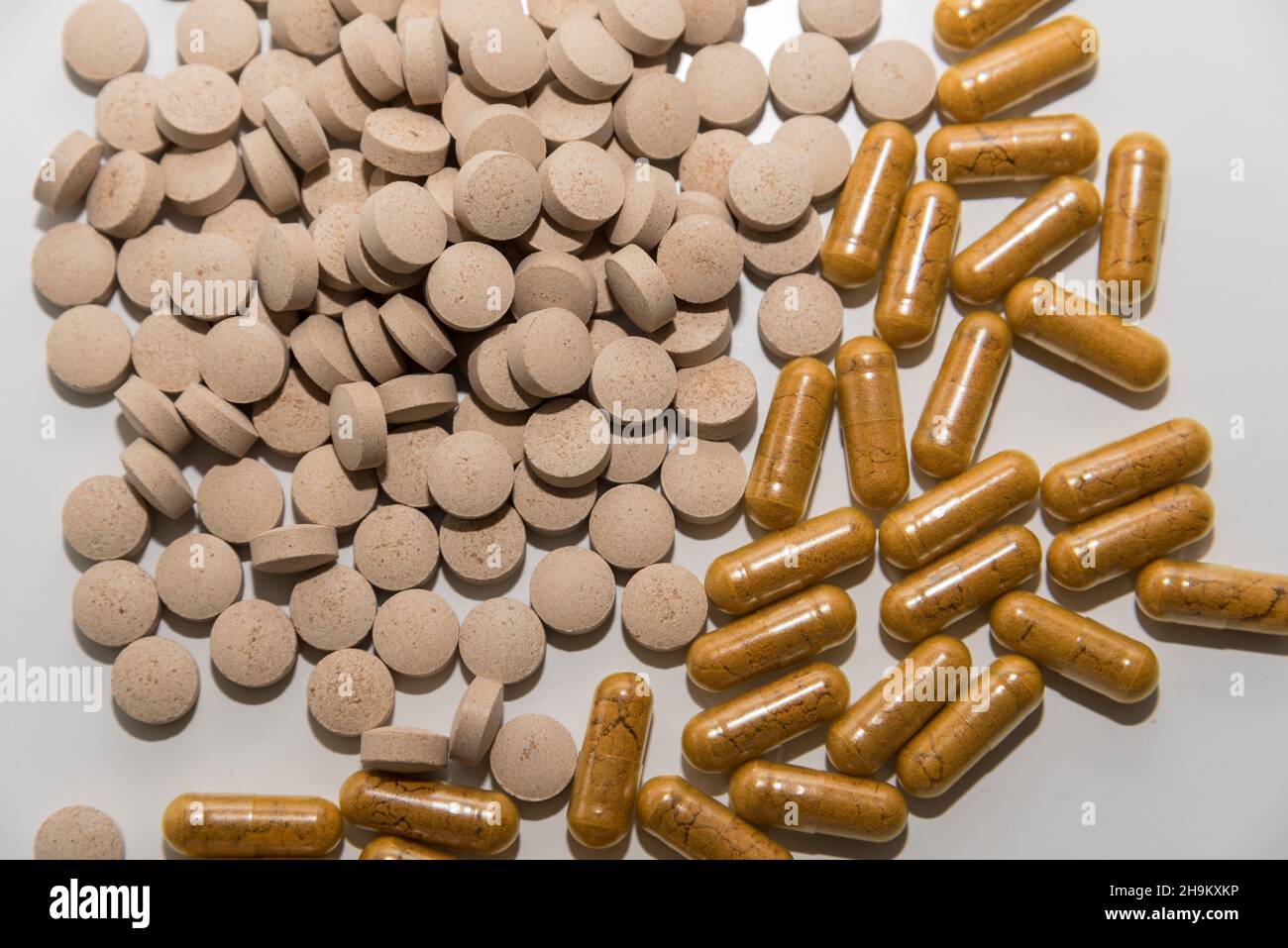 Transparent capsules with yellow powder and light brown pills on white ...