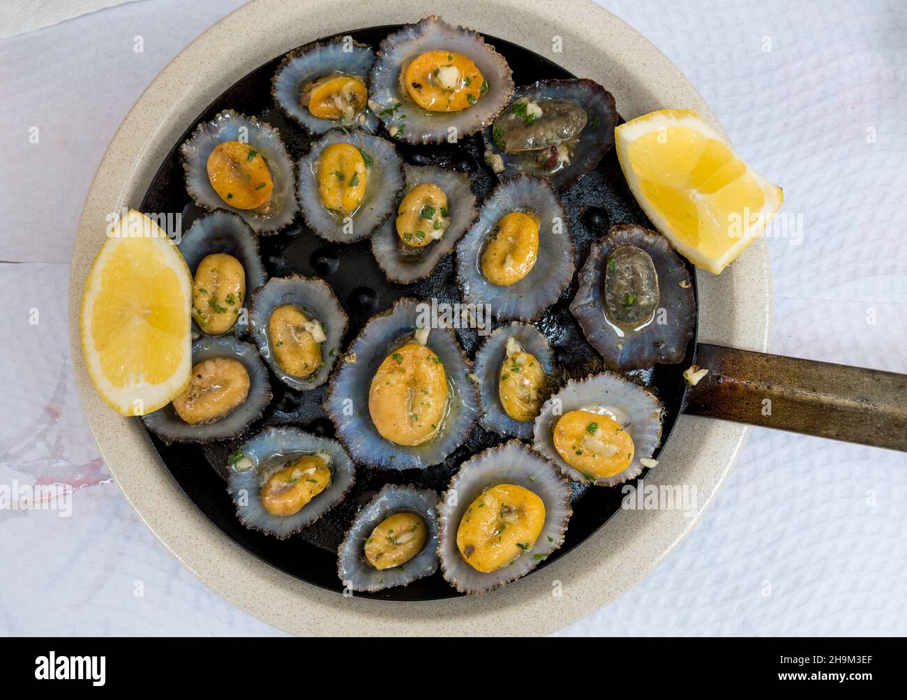 tasty seafood - grilled limpets served with lemon Stock Photo - Alamy