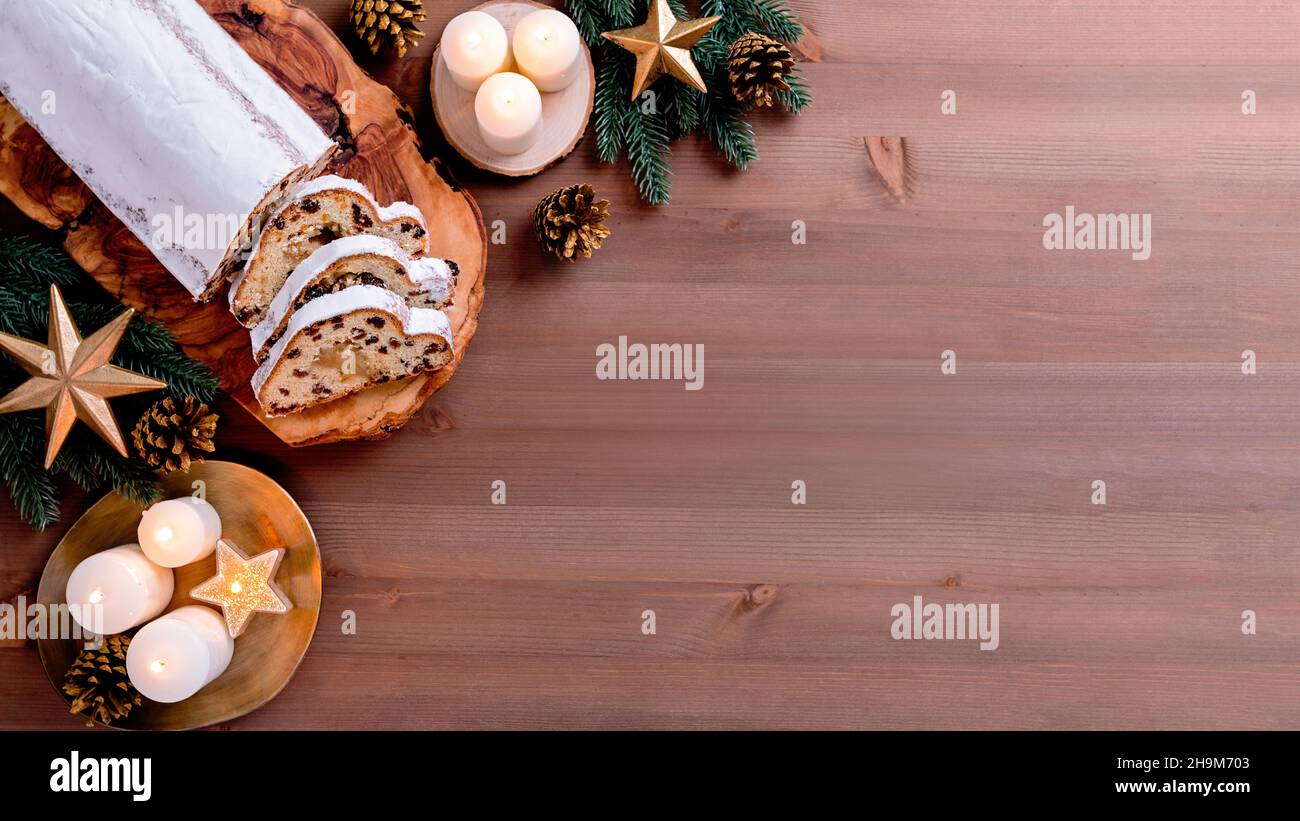 Web banner with Christmas Stollen cake and golden decor on brown wooden ...