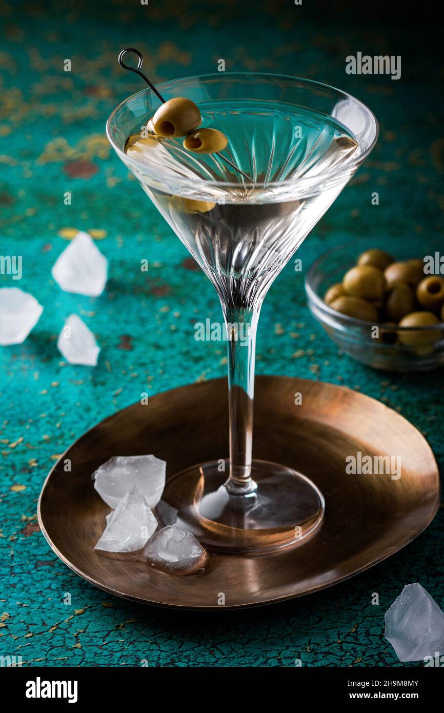 Dirty martini cocktail closeup in back light with olives garnish on ...