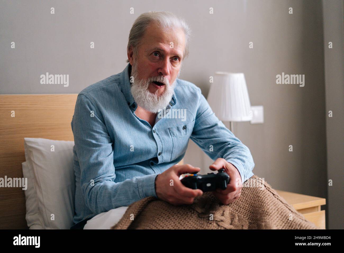 Front view of focused gray-haired senior male playing online video game ...