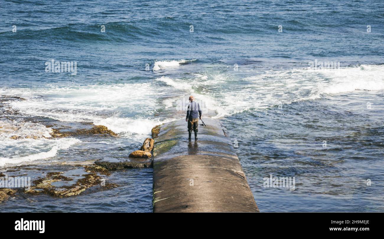 Fisherman standing on a pier and looking at rough sea Stock Photo - Alamy
