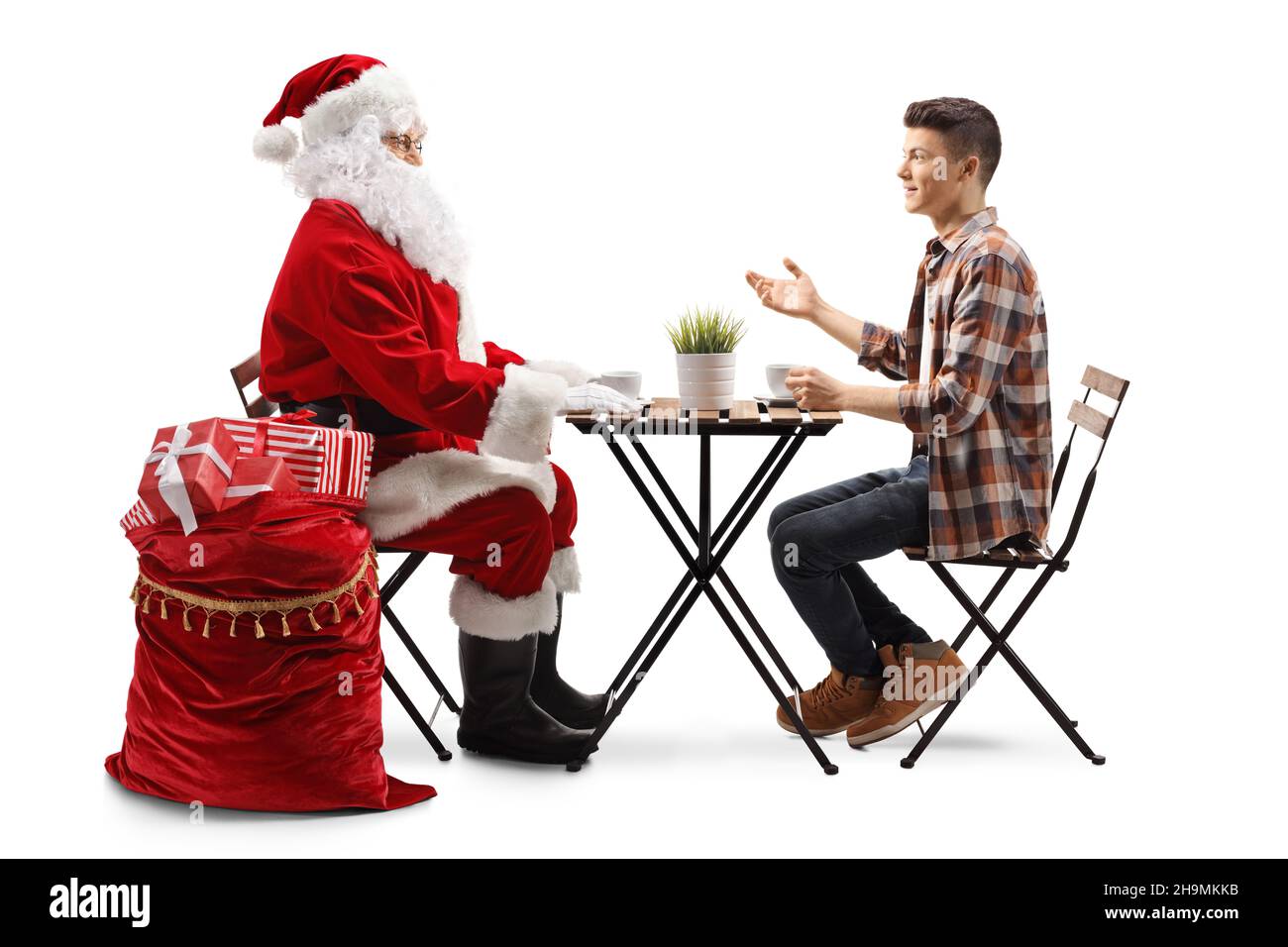 Santa Claus sitting at a table and listening to a young man talking and ...