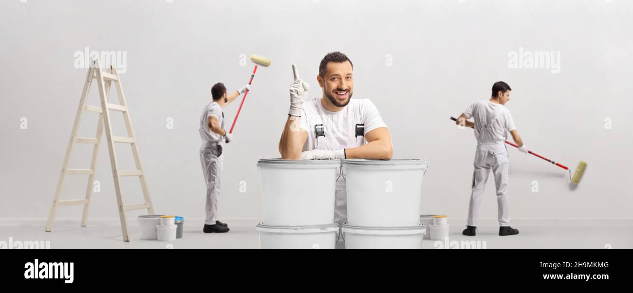 House painter leaning on buckets and pointing up and other painters ...