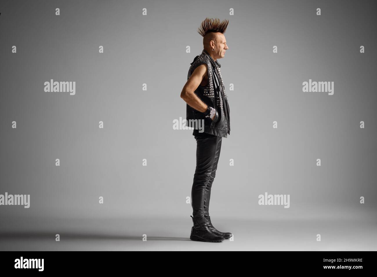Full length profile shot of a punk man with a mohawk isolated on gray ...