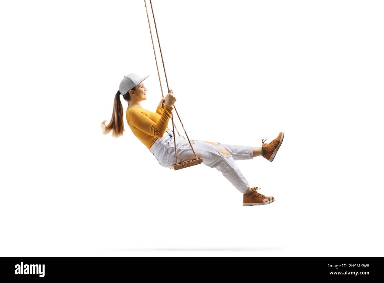 Full length profile shot of a young trendy female swinging on a wooden ...