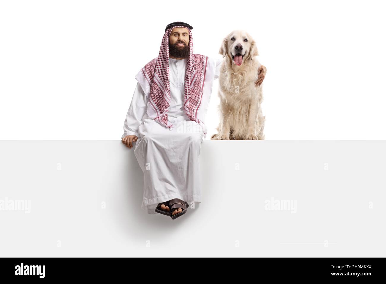 Saudi arab man sitting on a blank panel with a retriever dog isolated ...
