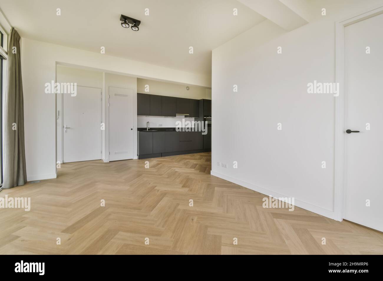 Huge room with parquet floor and kitchen in the corner Stock Photo - Alamy