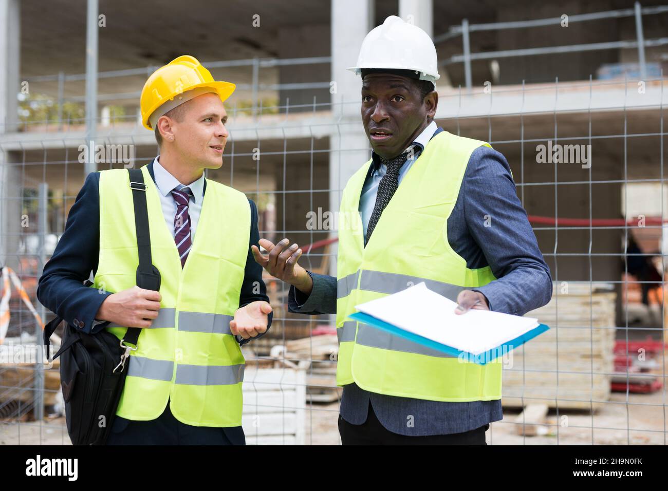 Builders talking about work outdoors Stock Photo - Alamy