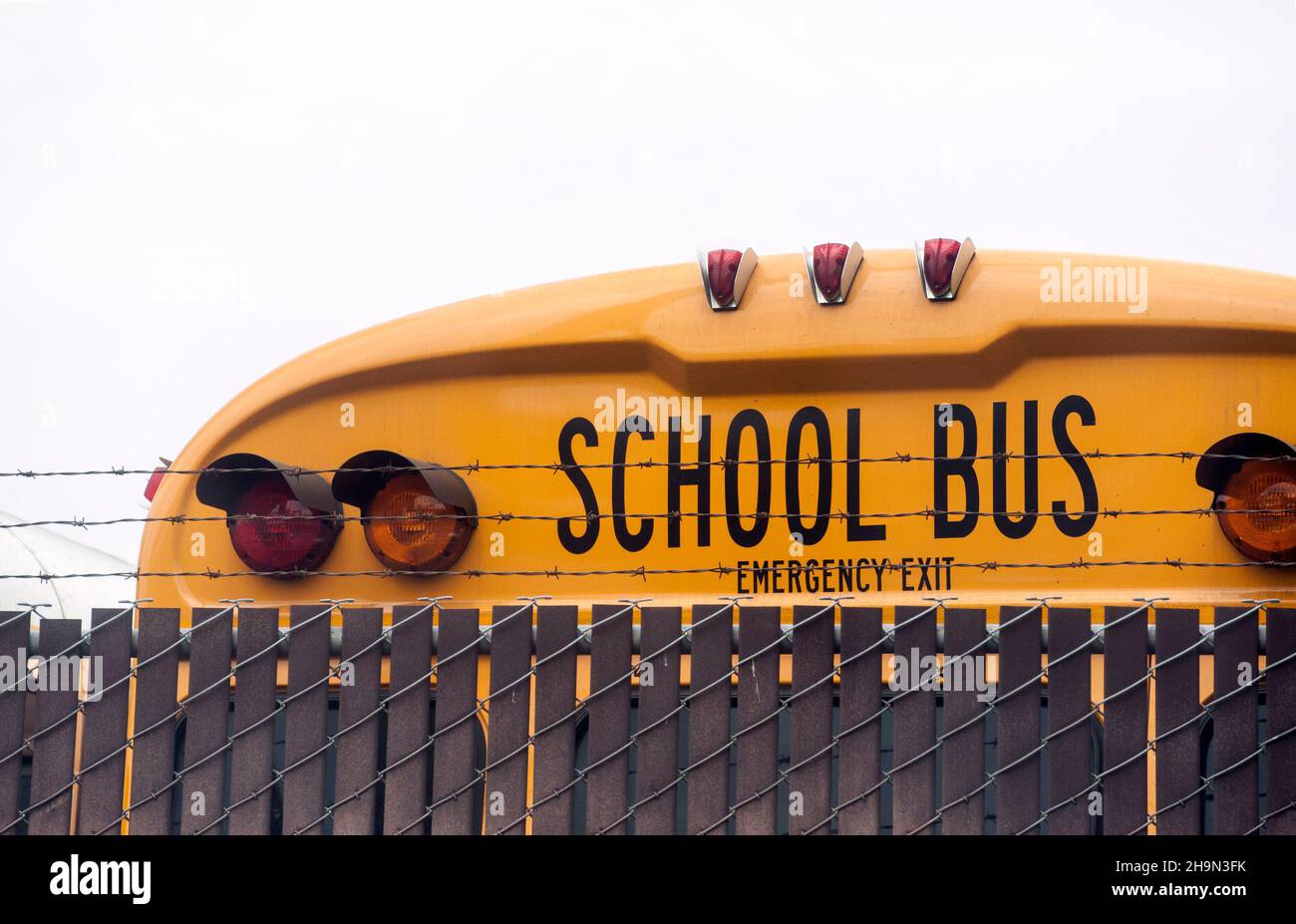 School bus parked behind a fenced in area with barbed wire Stock Photo ...