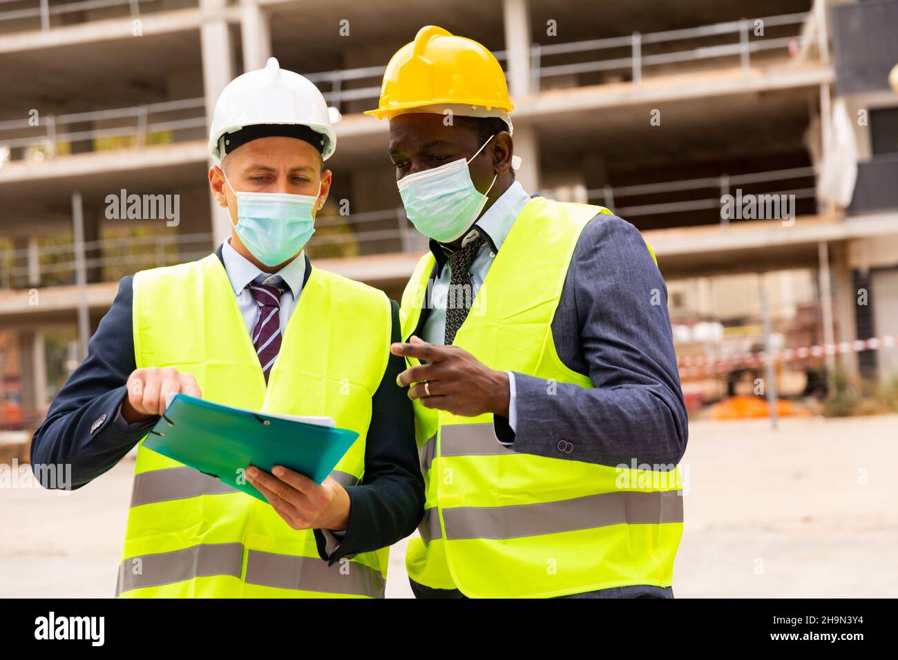 Engineers in masks standing on construction site Stock Photo - Alamy