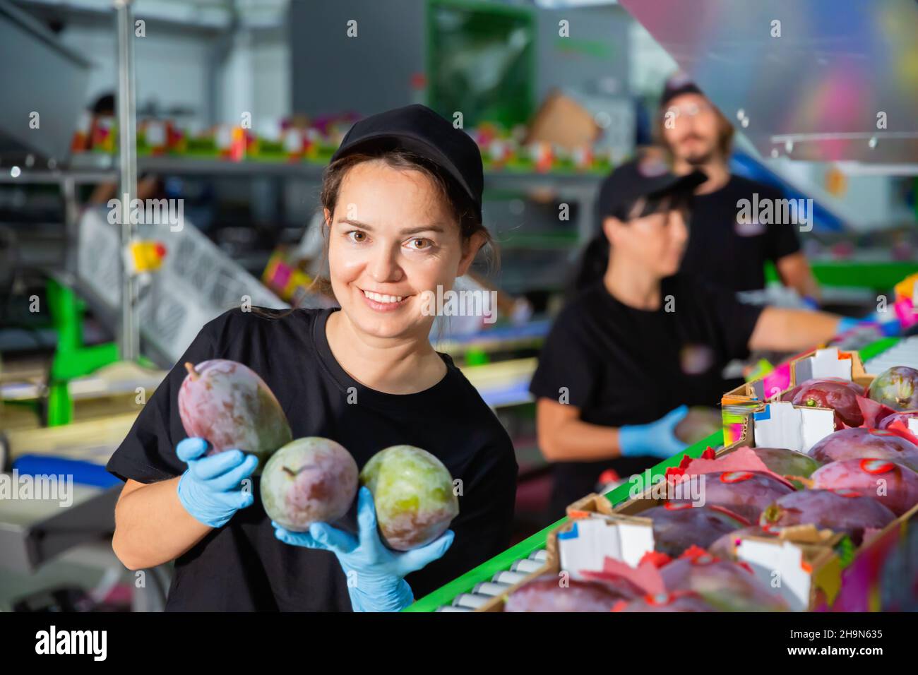 Portrait of positive female employee on fruit sorting department ...