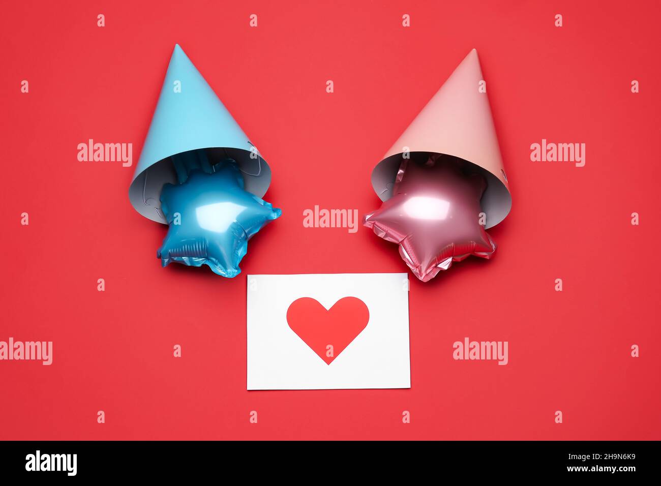 Beautiful balloons, party hats and heart on red background Stock Photo ...