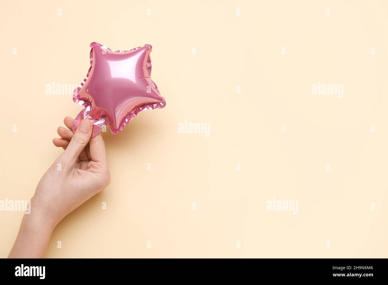 Female hand with beautiful balloon on beige background Stock Photo - Alamy