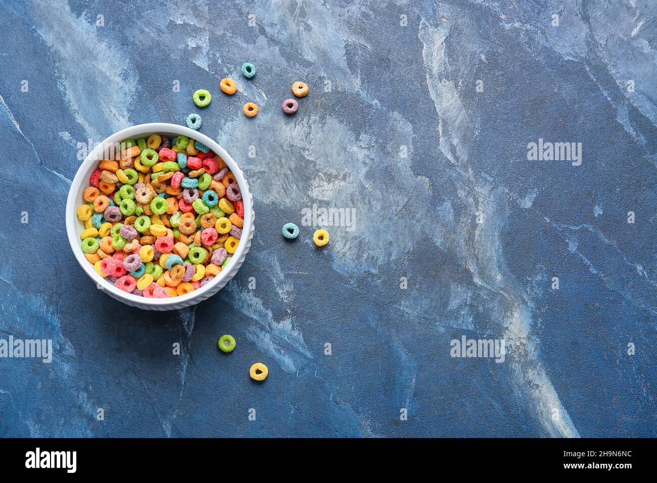 Bowl of colorful cereal rings on color background Stock Photo - Alamy