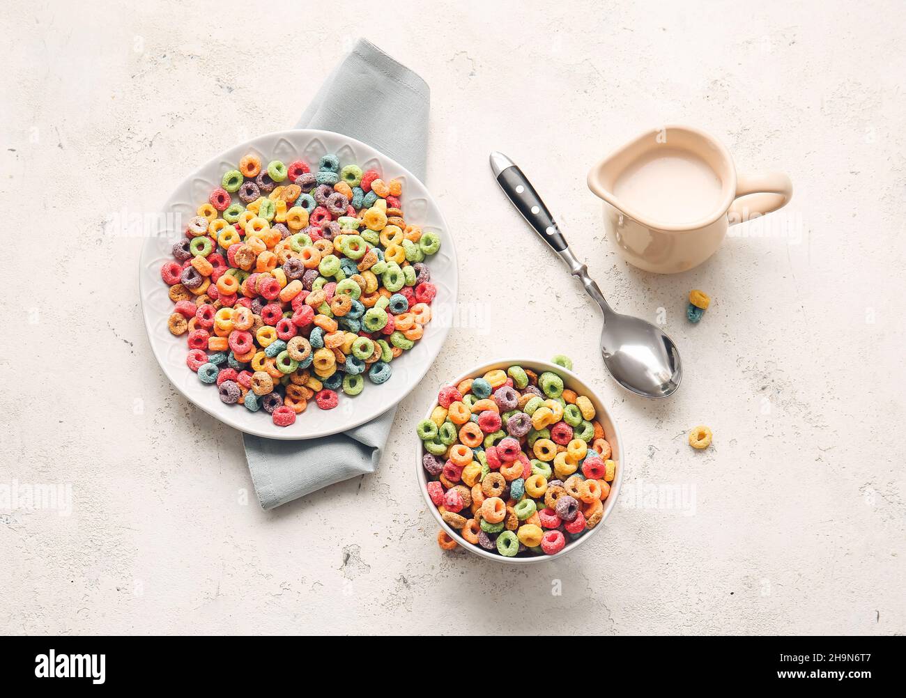 Bowl and plate of colorful cereal rings on light grunge background ...